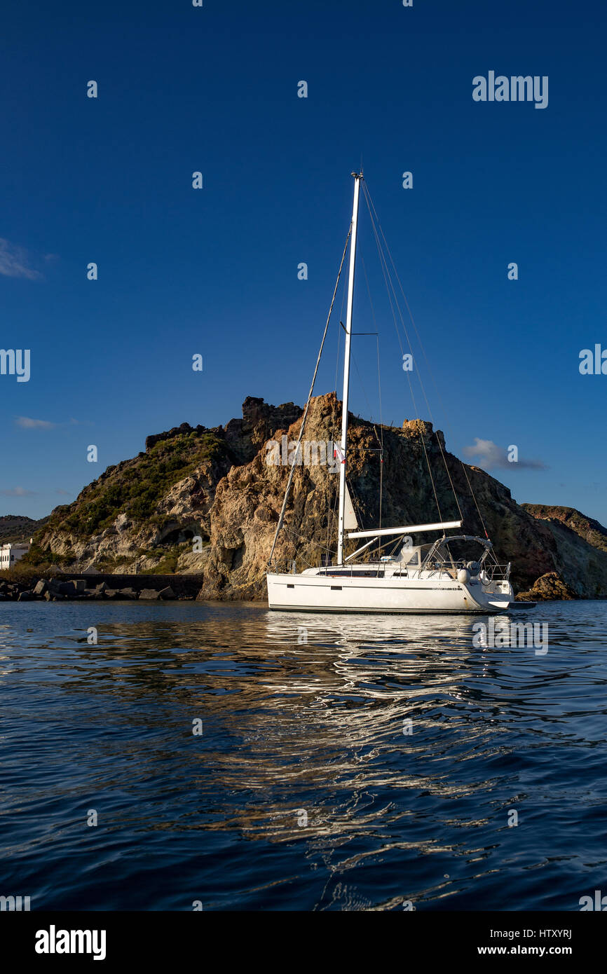 Sailing boat, yacht at a sea rock, small volcanic isle. Mediterranean ...