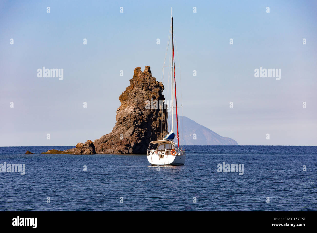 Sailing boat, yacht at a sea rock, small volcanic isle. Mediterranean ...