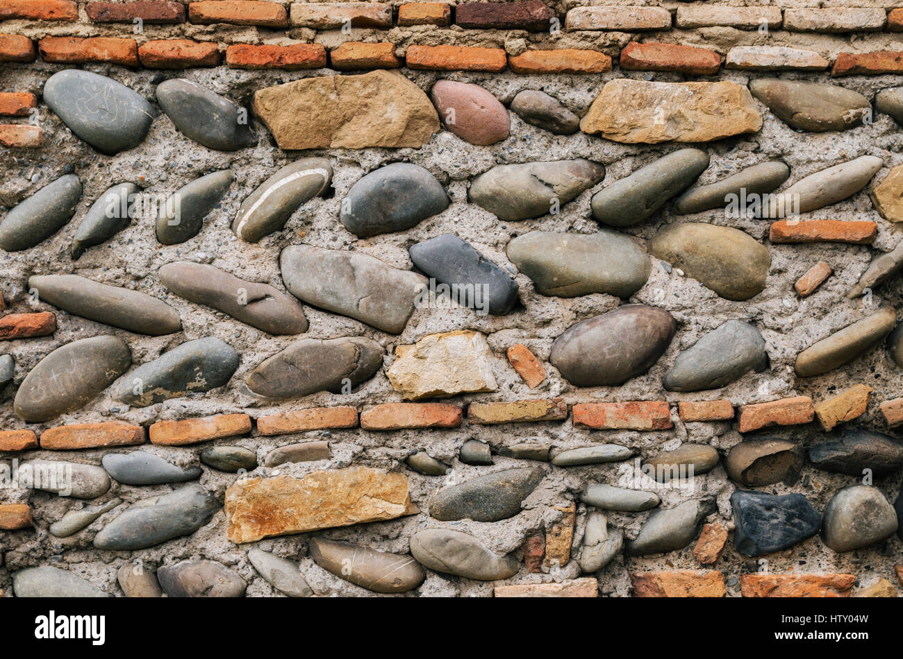 Ancient georgian natural stone wall of different sizes and brick ...