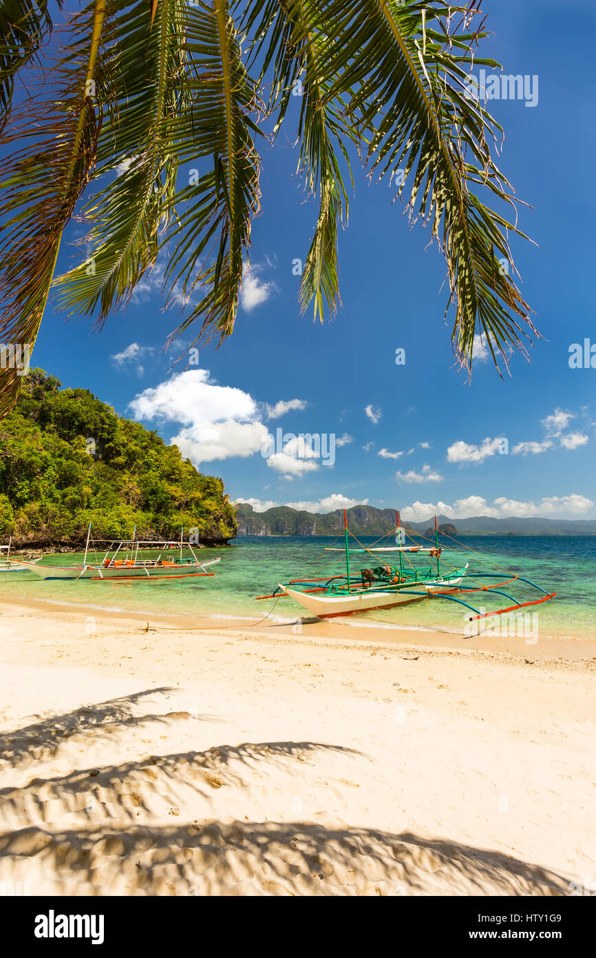 Traditional banca boats in clear water at the beach near Cudugnon Cave ...