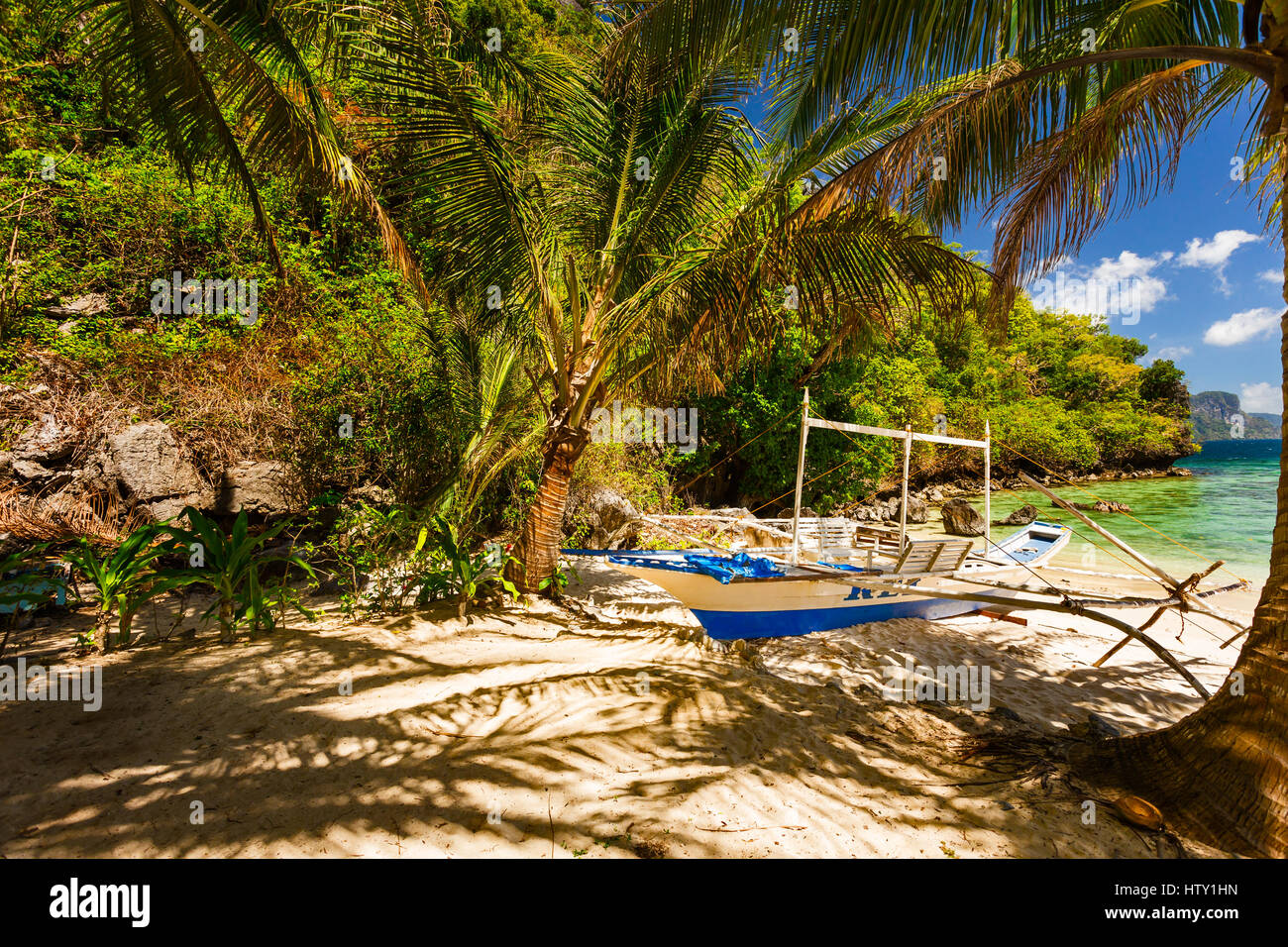 Traditional banca boat in the shade on the beach near Cudugnon Cave, El ...