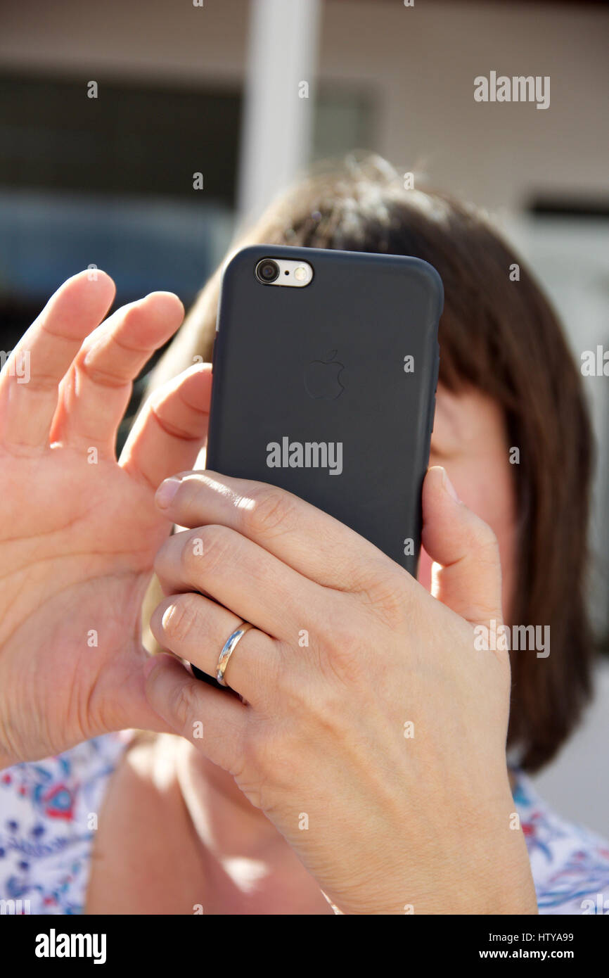 Lady using an Apple iPhone in the bright sunshine Stock Photo - Alamy