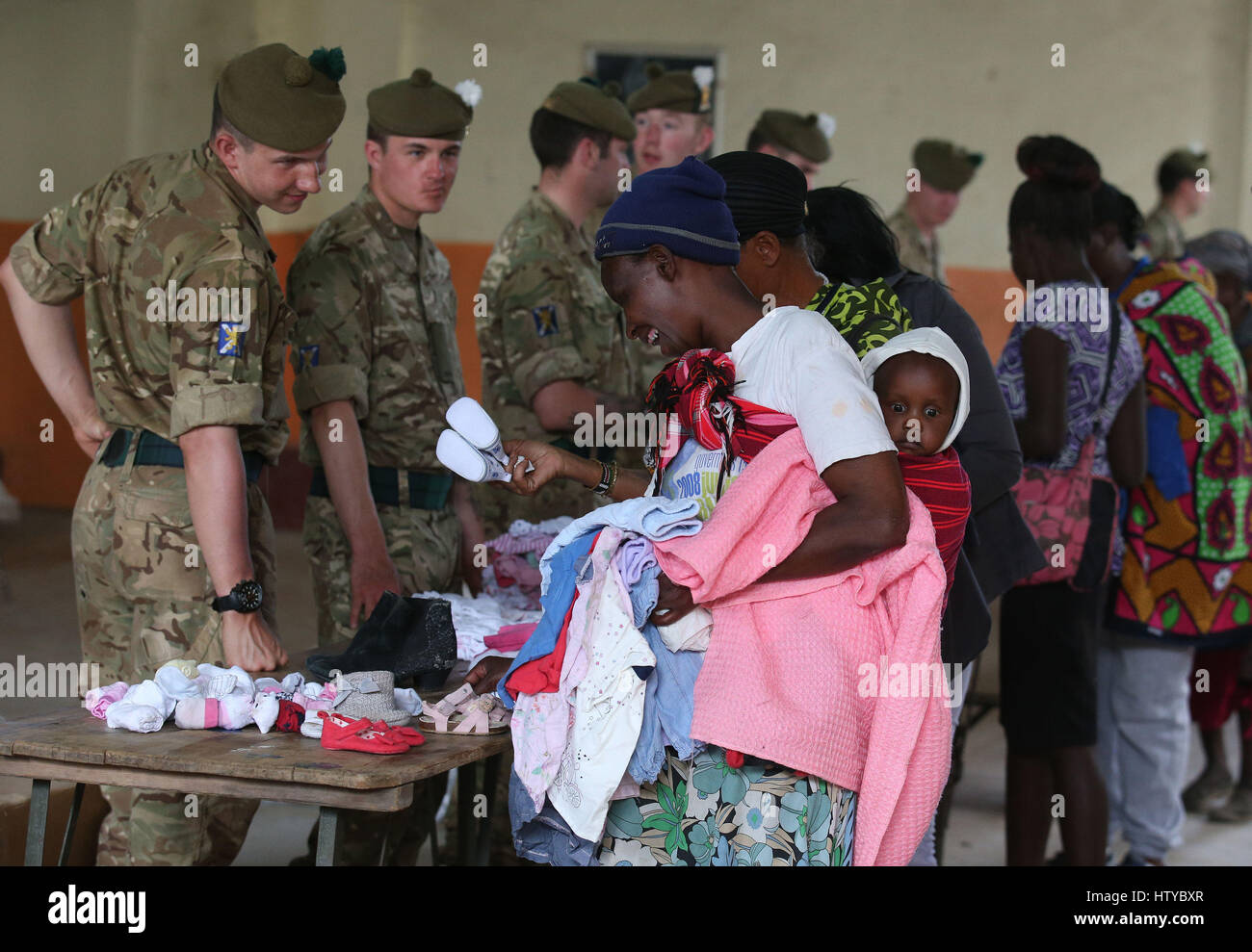 soldiers handing out donated clothes to villagers at a community hall ...