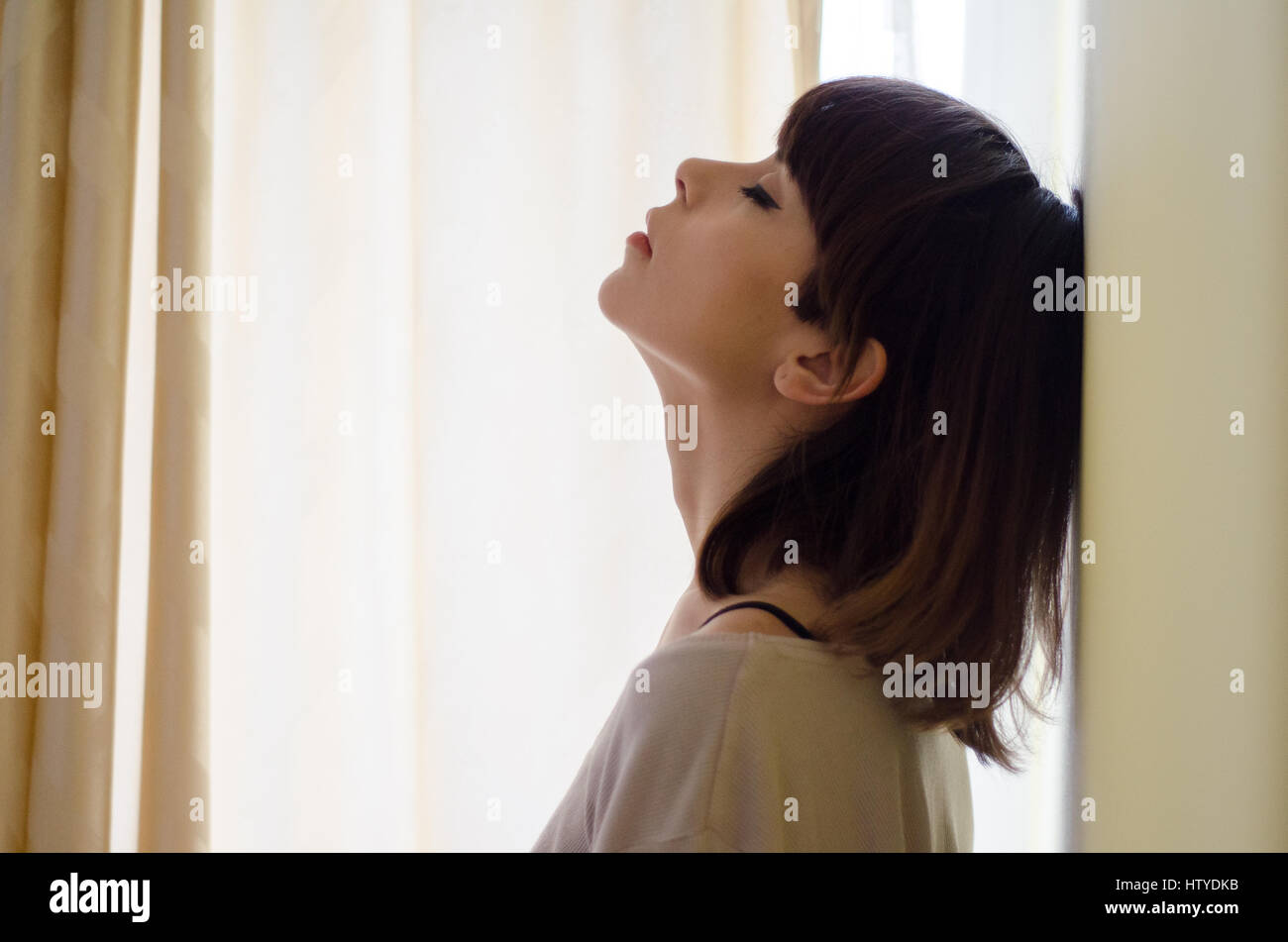 Portrait of a woman with head back leaning against a wall Stock Photo ...