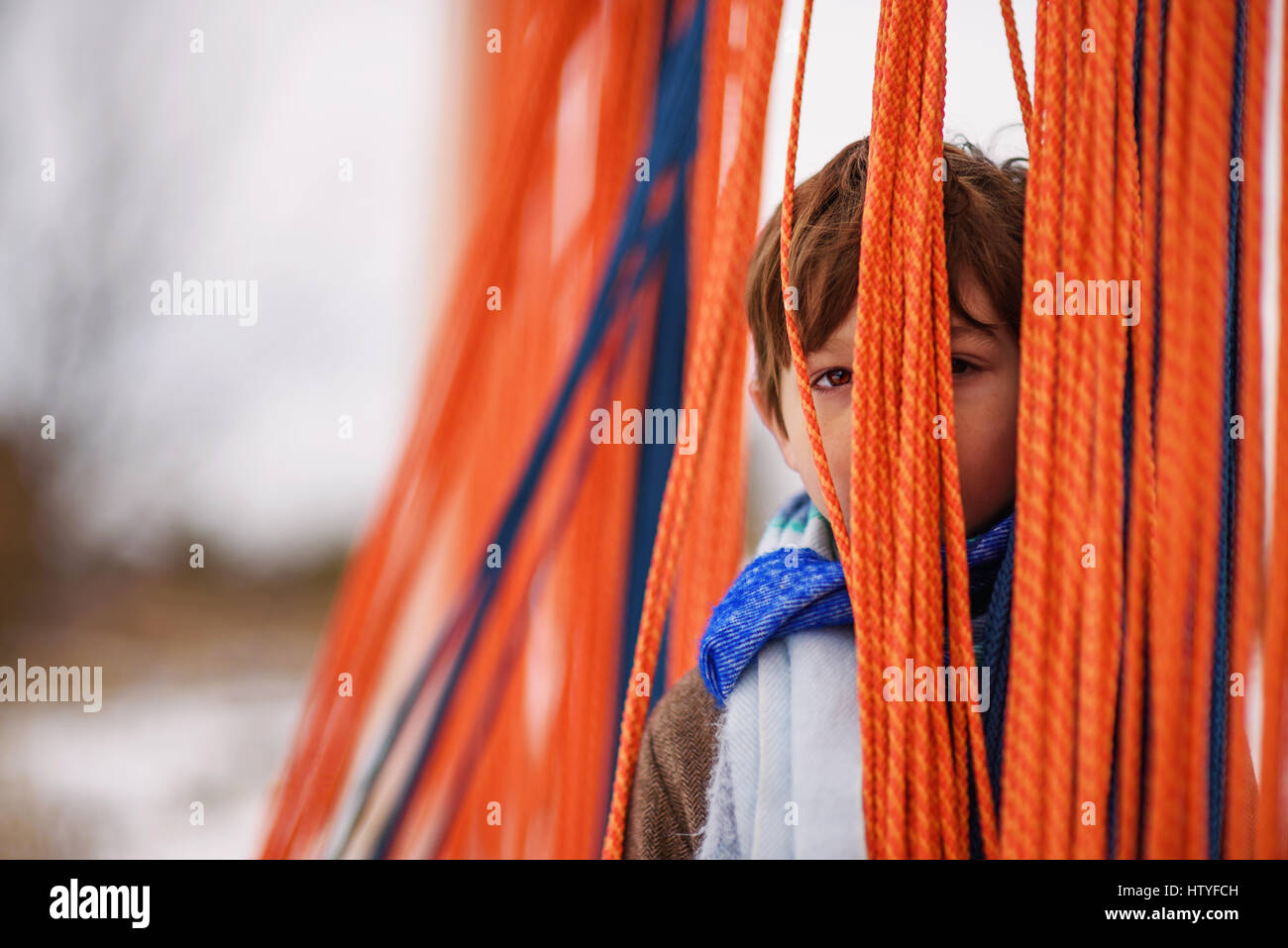 Boy hiding behind ropes in a playground Stock Photo - Alamy
