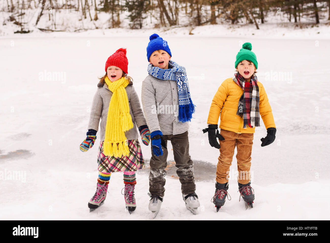 Three children on ice skates singing carols Stock Photo - Alamy