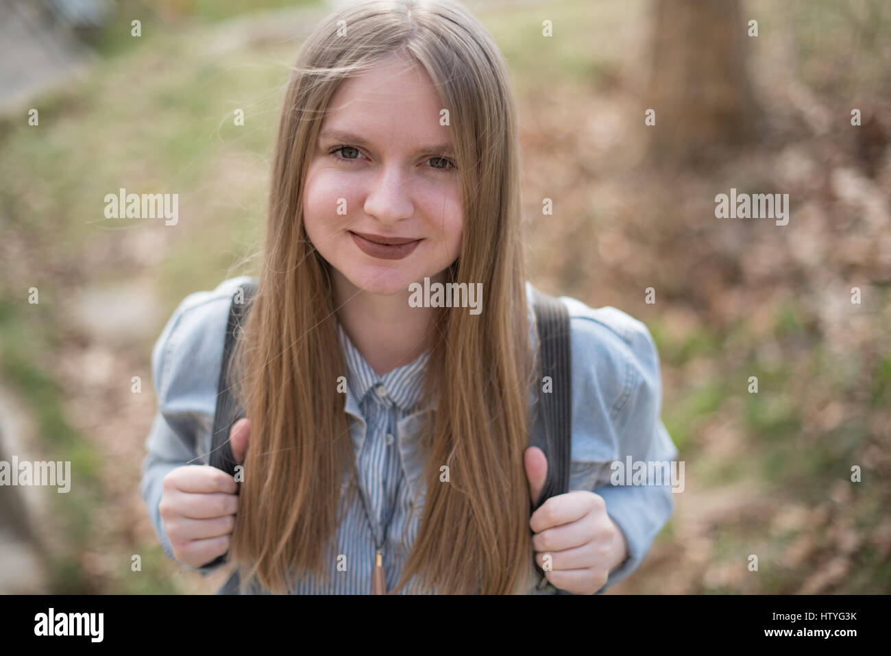 Portrait of a woman holding straps of her backpack Stock Photo - Alamy