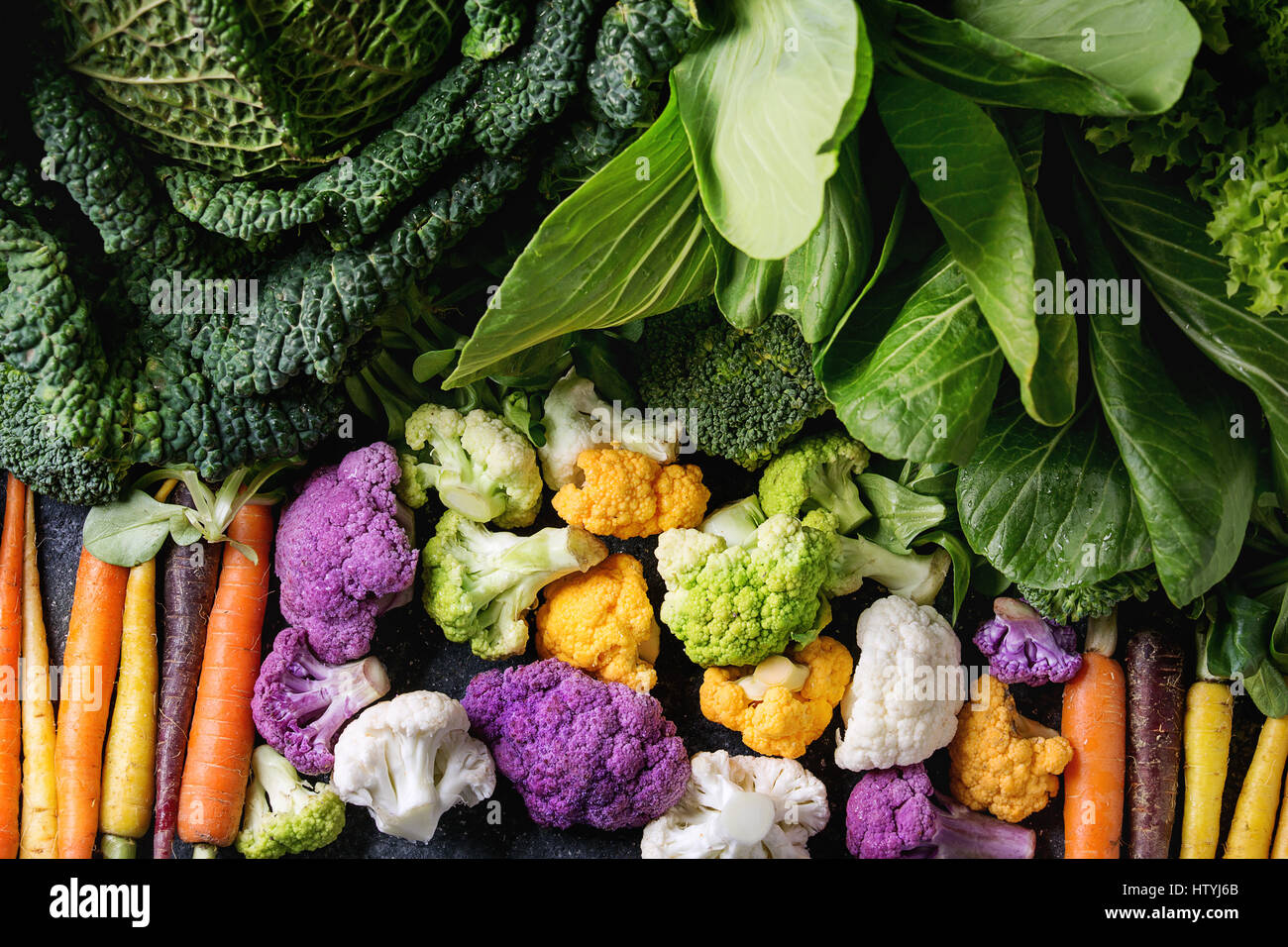 Variety of raw green vegetables salads, lettuce, bok choy, corn ...