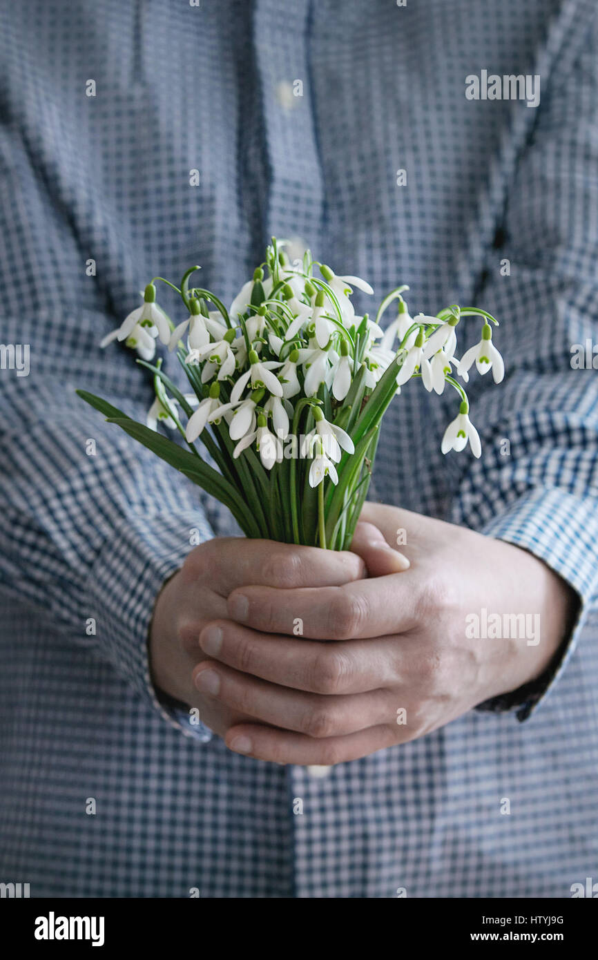 Bouquet of wild snowdrops in male hands. Man in blue and white ...