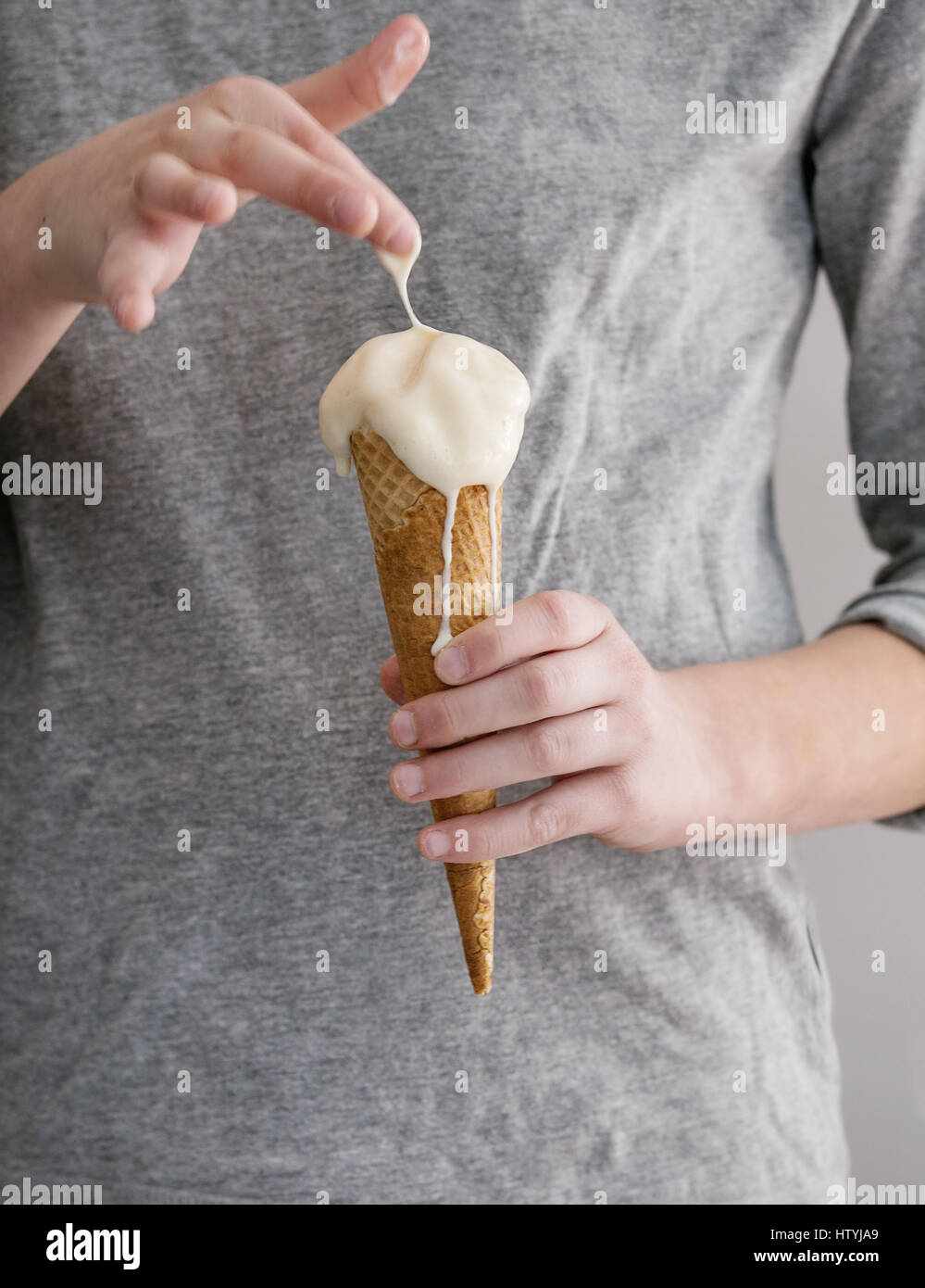 Vanilla soft elastic ice cream in waffle cone in boy hands. Boy in gray ...