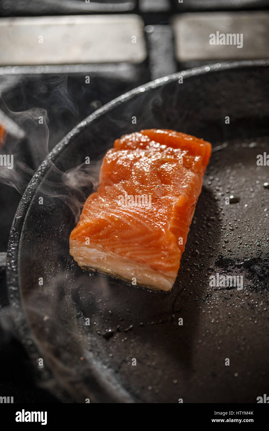 Frying salmon in black pan in restaurant kitchen Stock Photo - Alamy