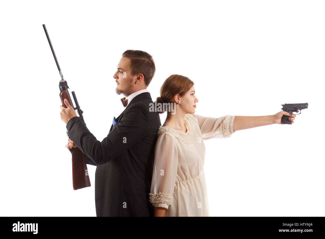 A man in a suit and a girl in a dress both holding guns Stock Photo - Alamy