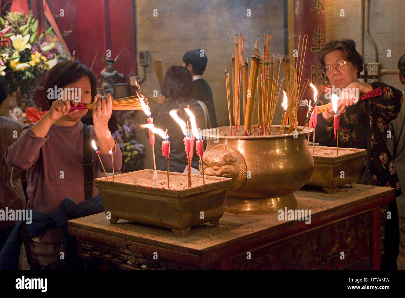 Local people at the Man Mo Temple in Hong Kong lighting incense sticks ...