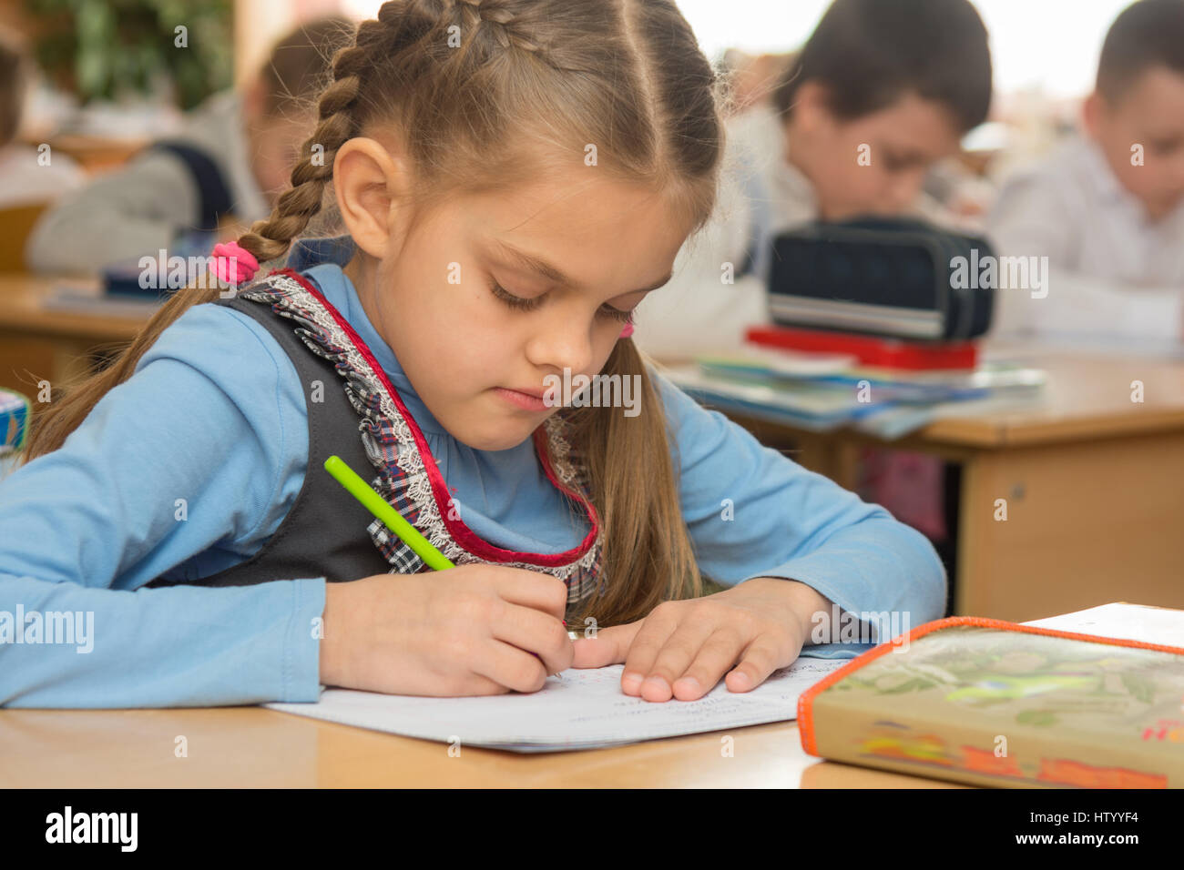 First grader in class writing in notebook Stock Photo - Alamy