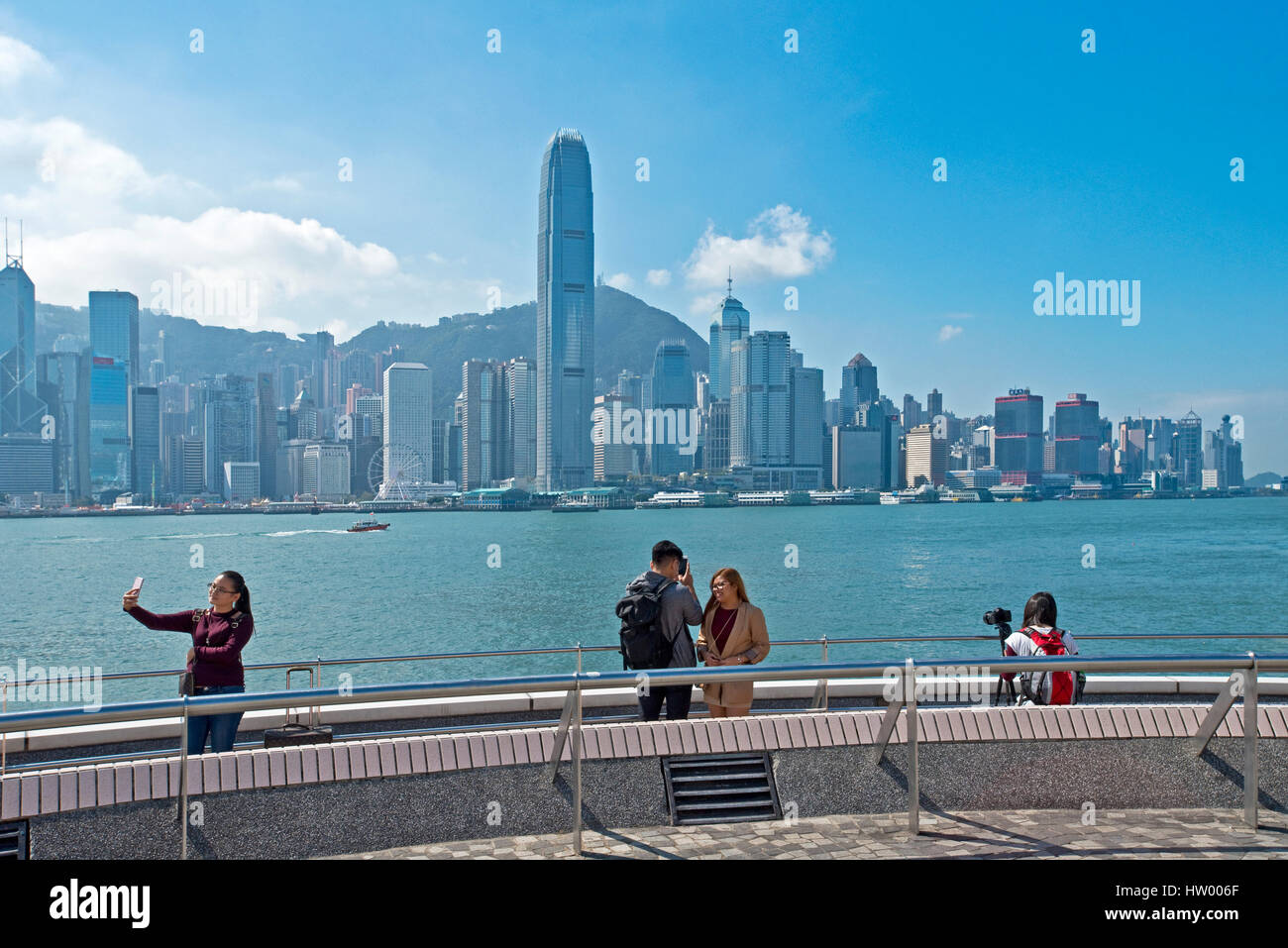 Tourists taking pictures photographs from the Kowloon Public Pier of the skyscrapers along Hong ...