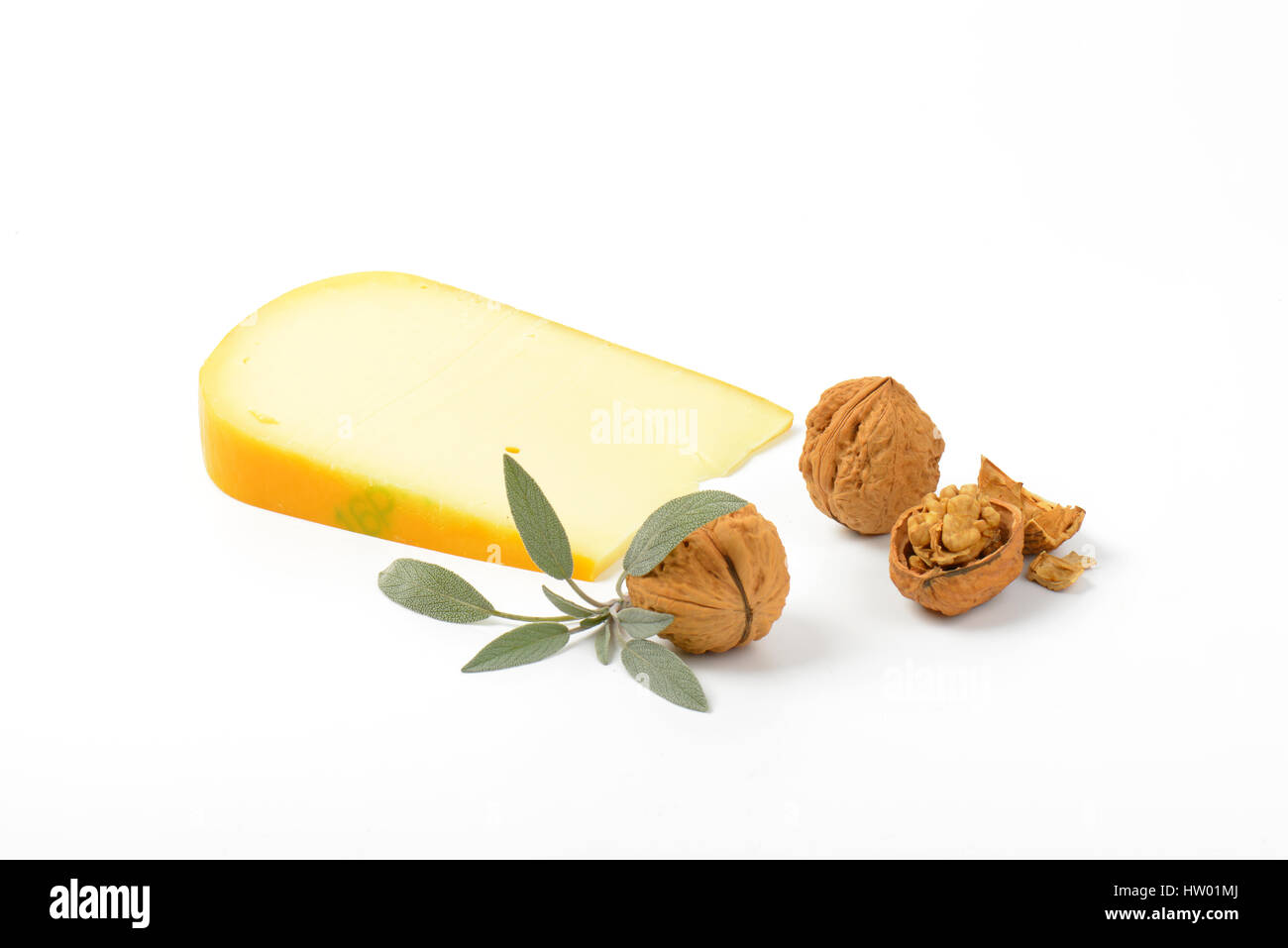 slice of gouda cheese with walnuts and sprig of sage on white ...