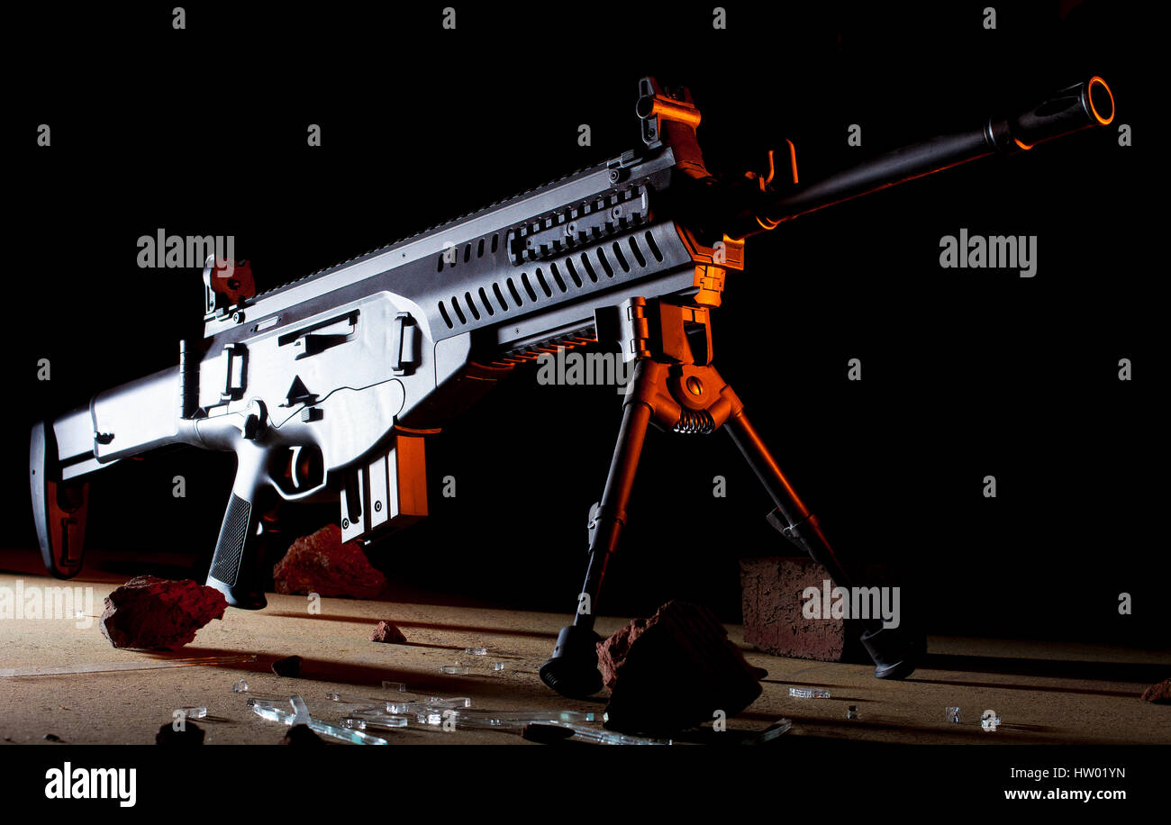 Semi automatic black rifle with orange light from the side on a dark ...