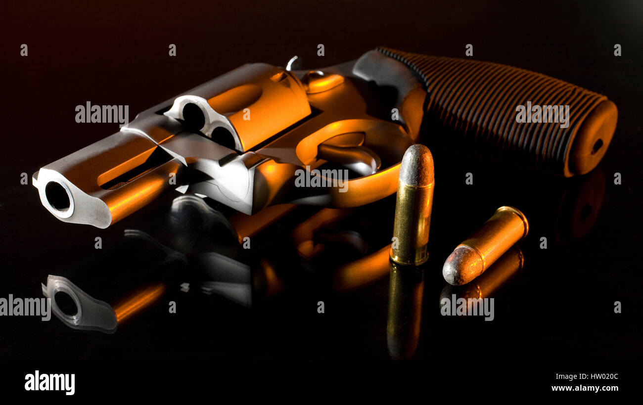 Revolver with cartridges on a dark background with orange side lighting ...
