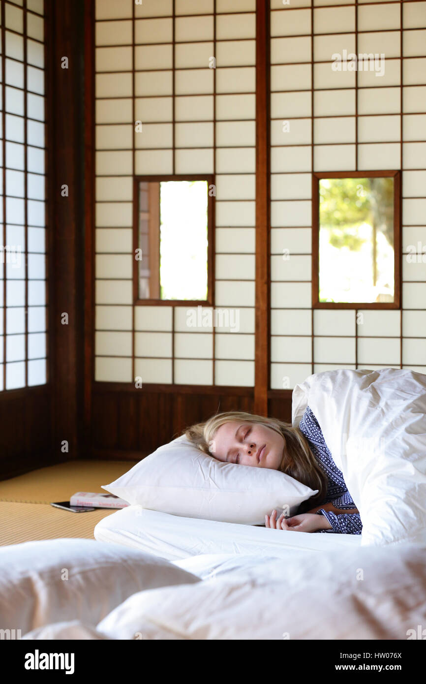 Caucasian woman wearing yukata in traditional Japanese house futon ...