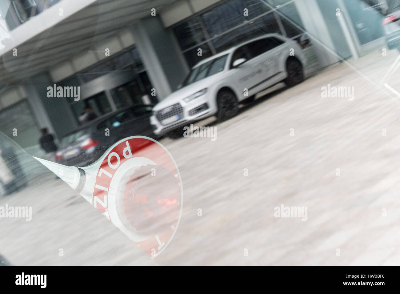 A police sign reflected in a car window and two civilian police cars in ...
