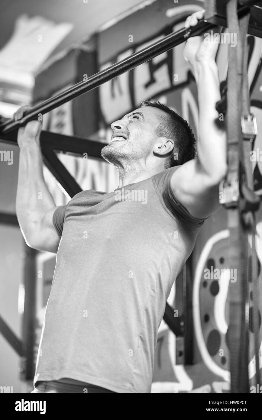 strong young man doing pull ups on a bar in a gym Stock Photo - Alamy