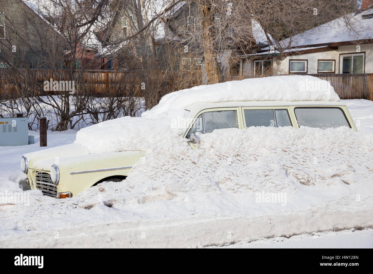 Frozen car underneath a lot of snow is completely stuck on the side of ...