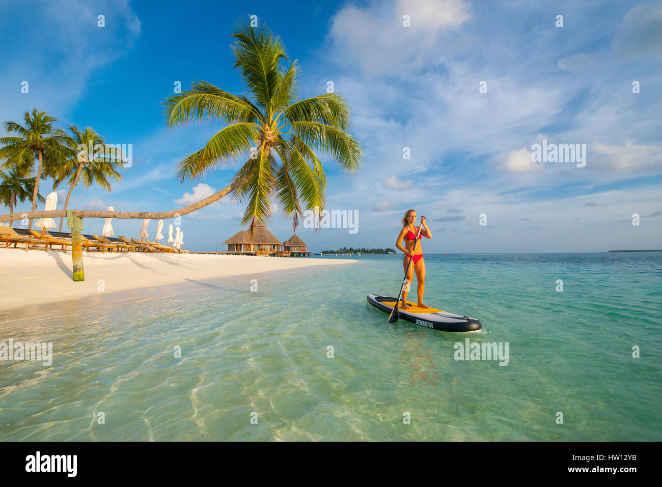 Maldives, Rangali Island. Conrad Hilton Resort. Woman on a paddleboard ...