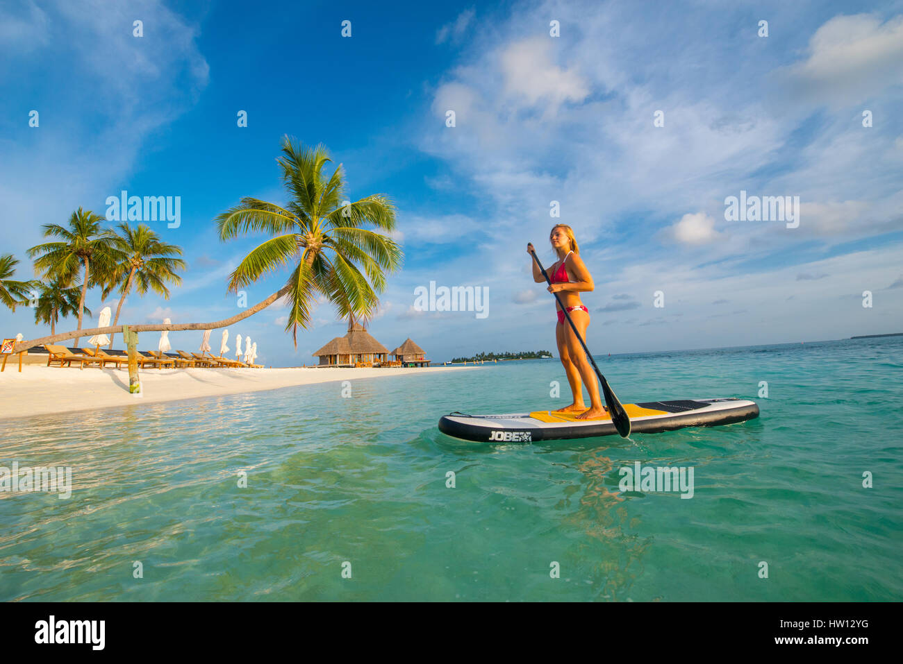 Maldives, Rangali Island. Conrad Hilton Resort. Woman on a paddleboard ...