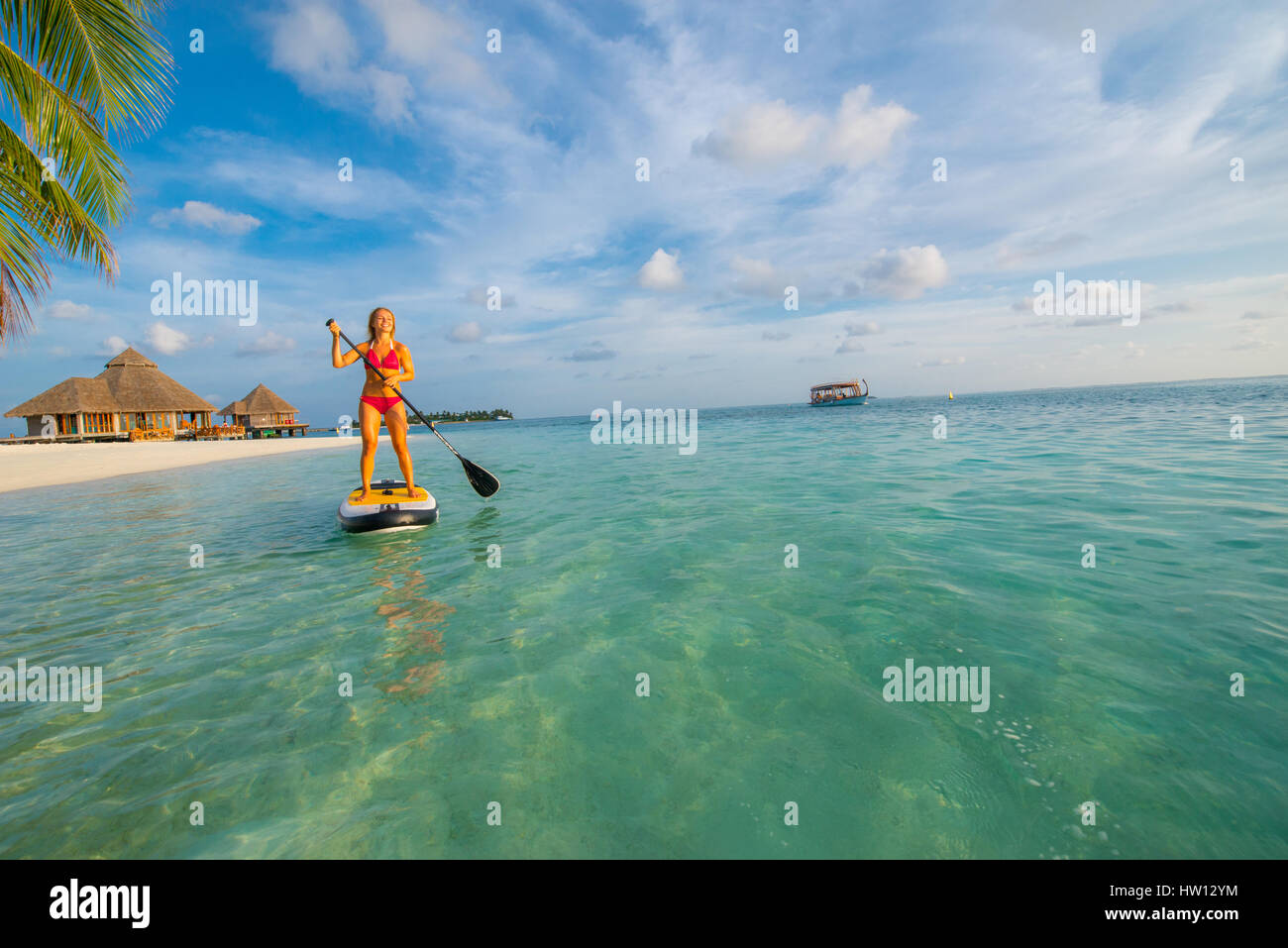 Maldives, Rangali Island. Conrad Hilton Resort. Woman on a paddleboard ...