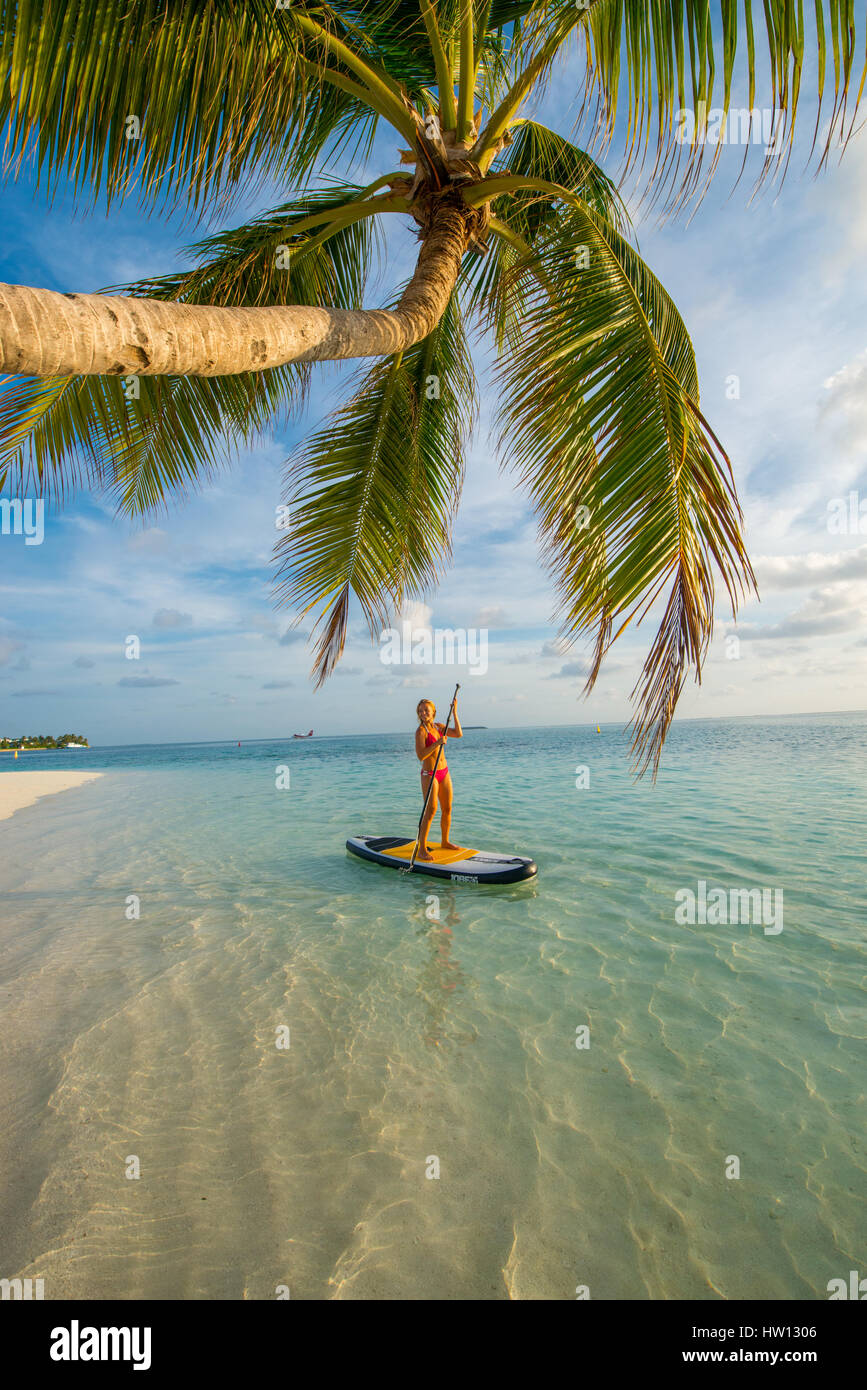 Maldives, Rangali Island. Conrad Hilton Resort. Woman on a paddleboard ...