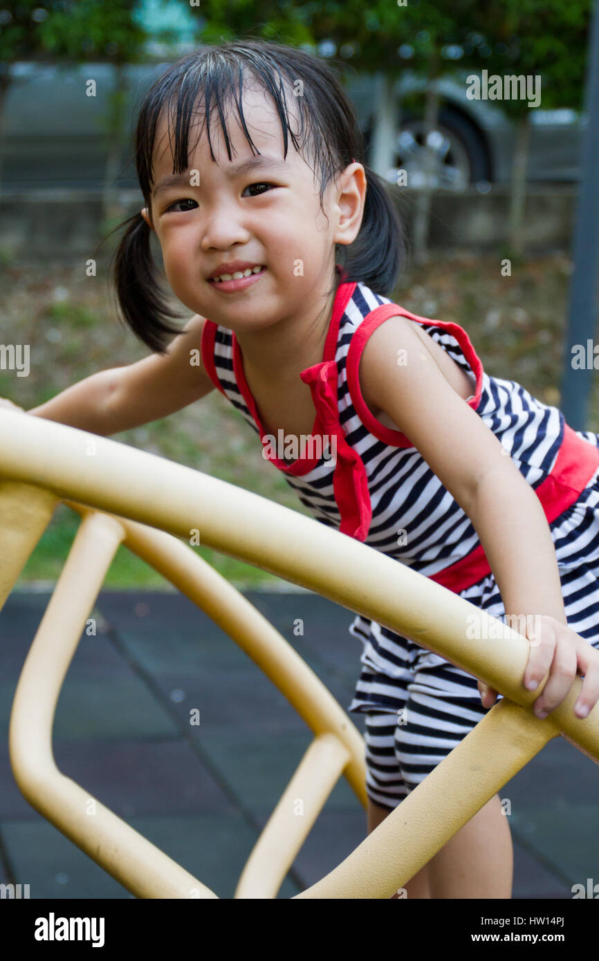 Asian Chinese toddler girl climbing a ladder on the outdoor playground ...