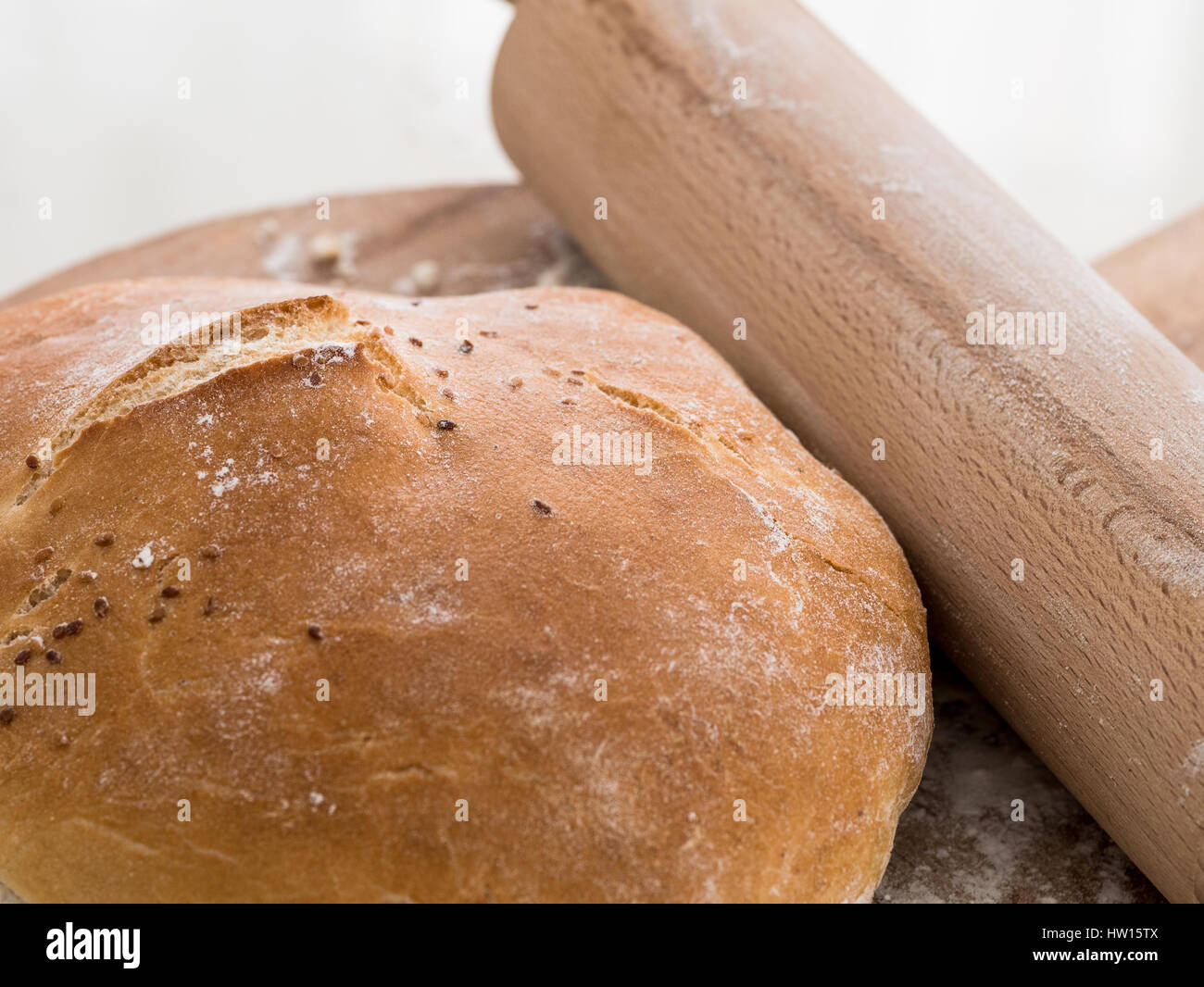 Round bun bread with a rolling pin on white table Stock Photo - Alamy