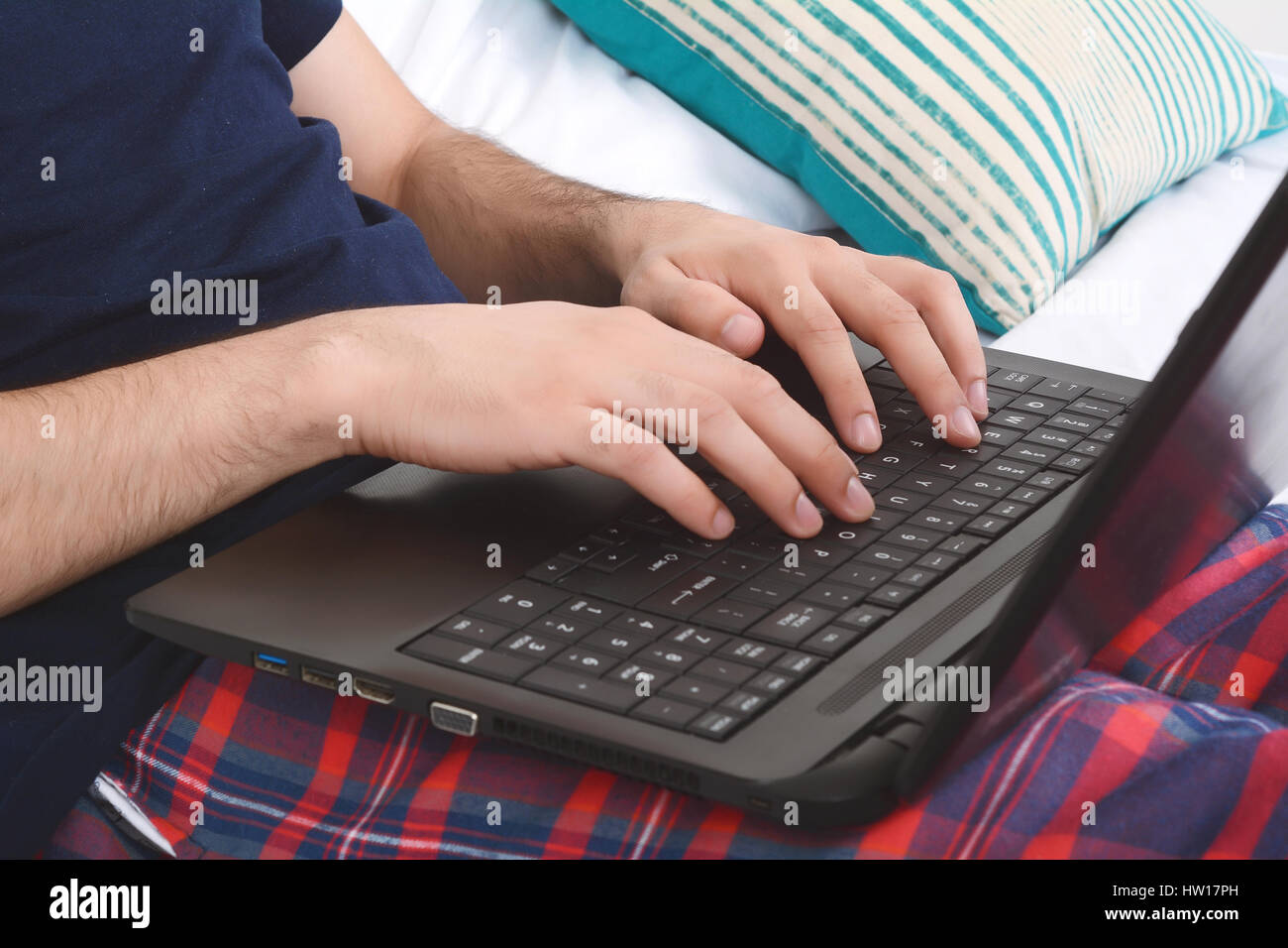 Attractive young man using his laptop in bed. Indoors Stock Photo - Alamy