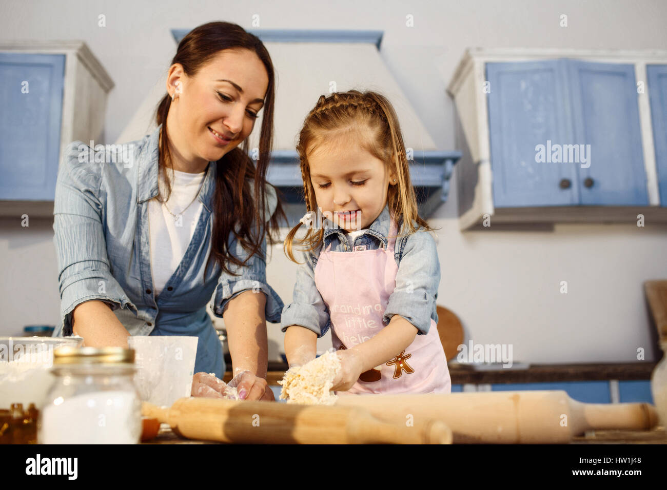 A girl is helping her mother cooking in kitchen Stock Photo - Alamy
