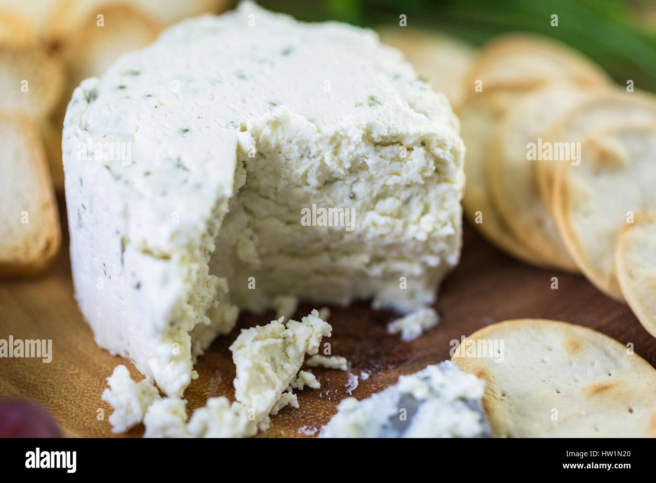 Soft flavored creamy cheese with garlic and fine herbs on a wood board ...