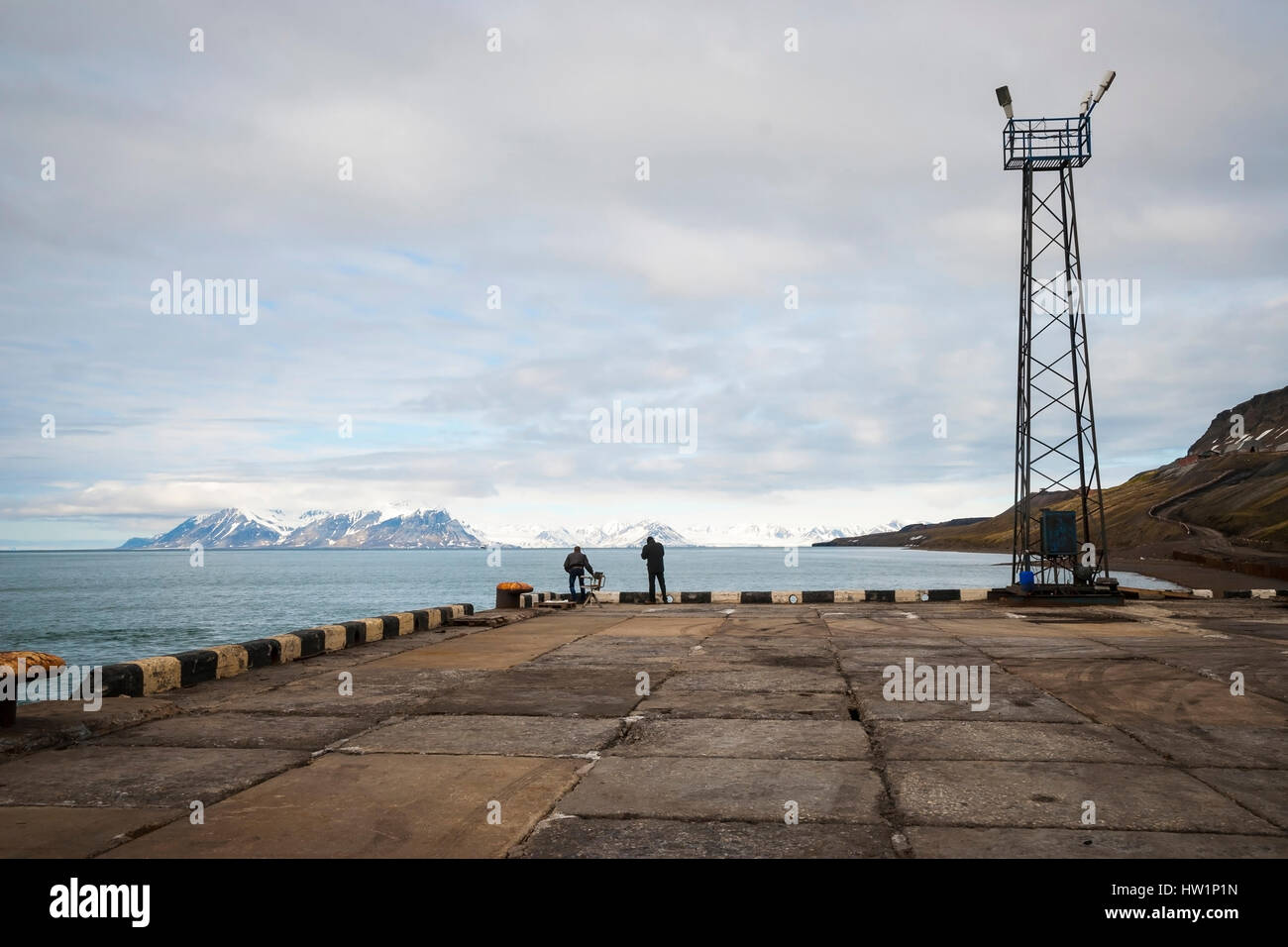 silhouette of two people fishing in Barentsburg port, Svalbard, Norway ...