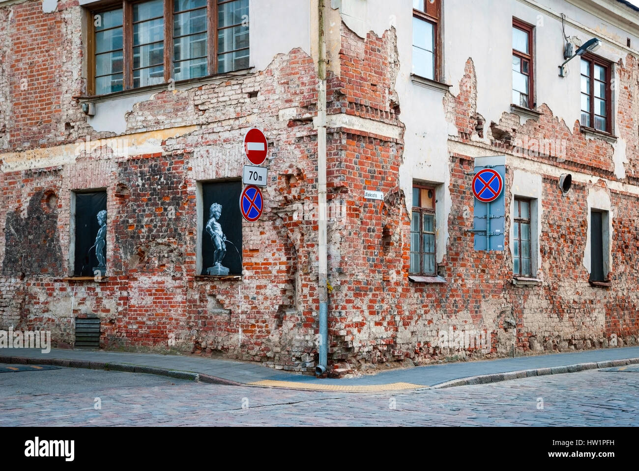View on brick building with damaged wall and road signs hanging on it ...