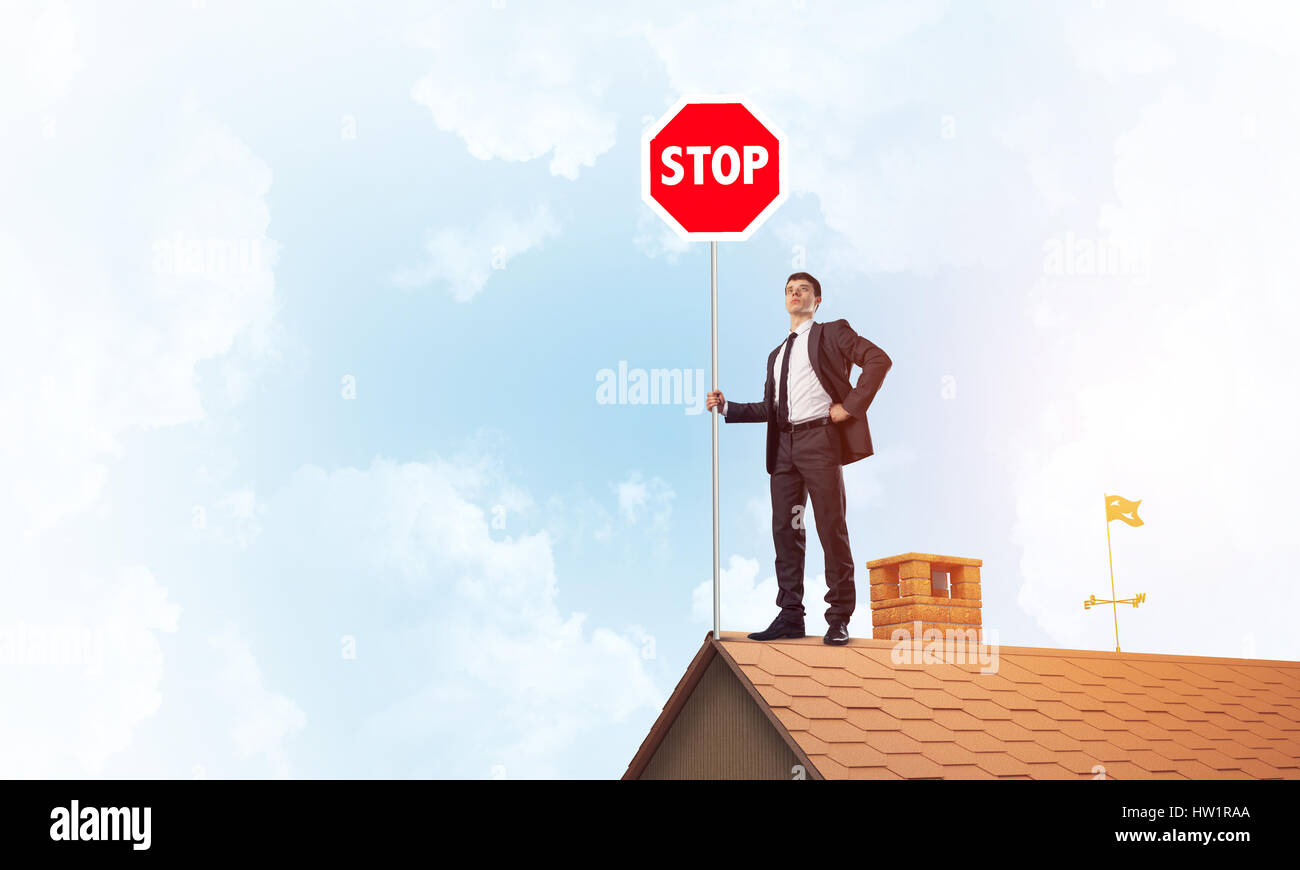 Caucasian businessman on brick house roof showing stop road sign Stock ...