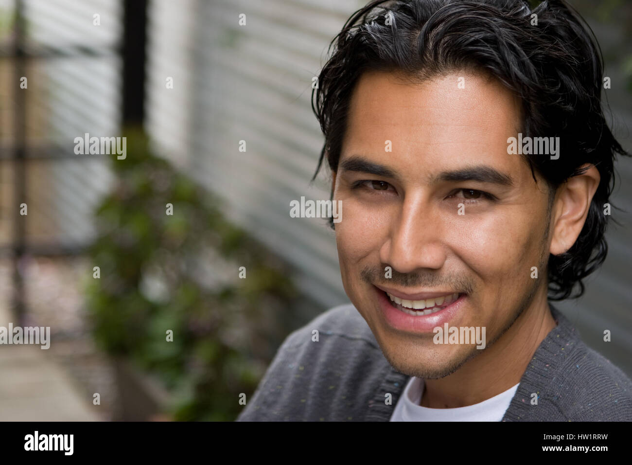 Happy Hispanic man smiling and standing outside Stock Photo - Alamy