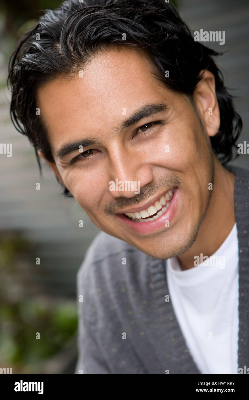 Happy Hispanic man smiling and standing outside Stock Photo - Alamy