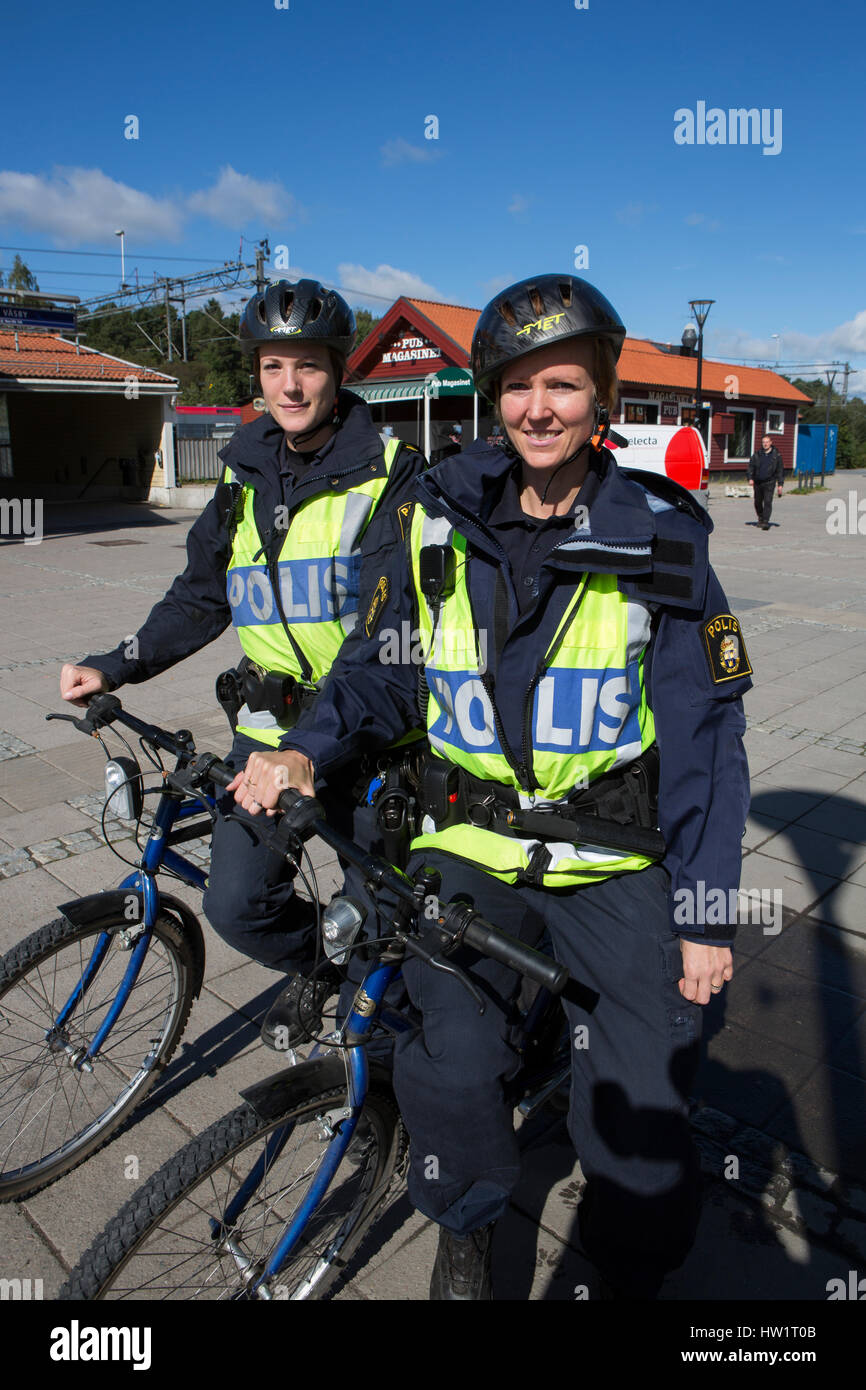 Two female police officers patrolling by bike in Upplands Vasby, Sweden ...