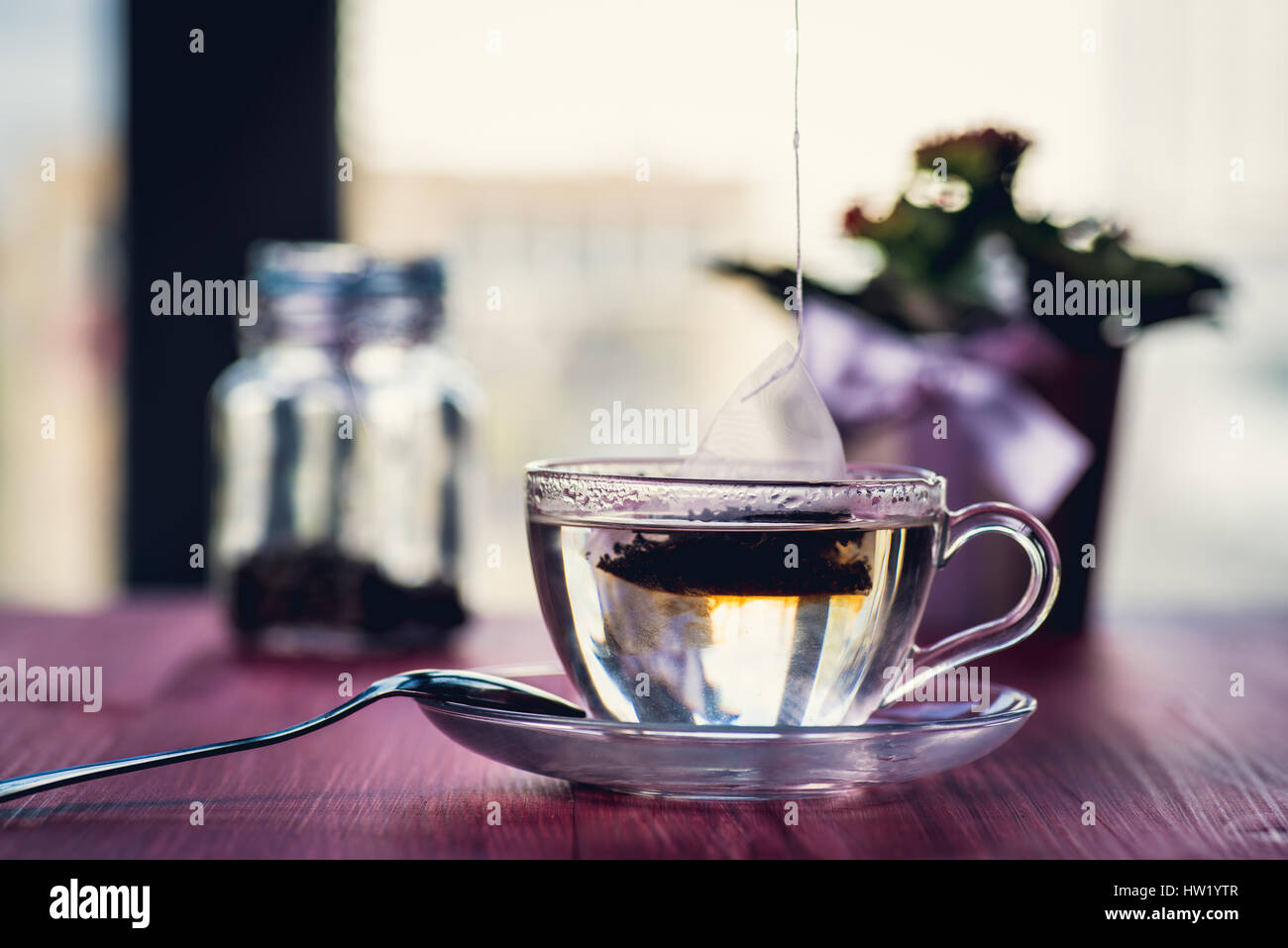 Putting tea bag into glass cup full of hot water Stock Photo - Alamy