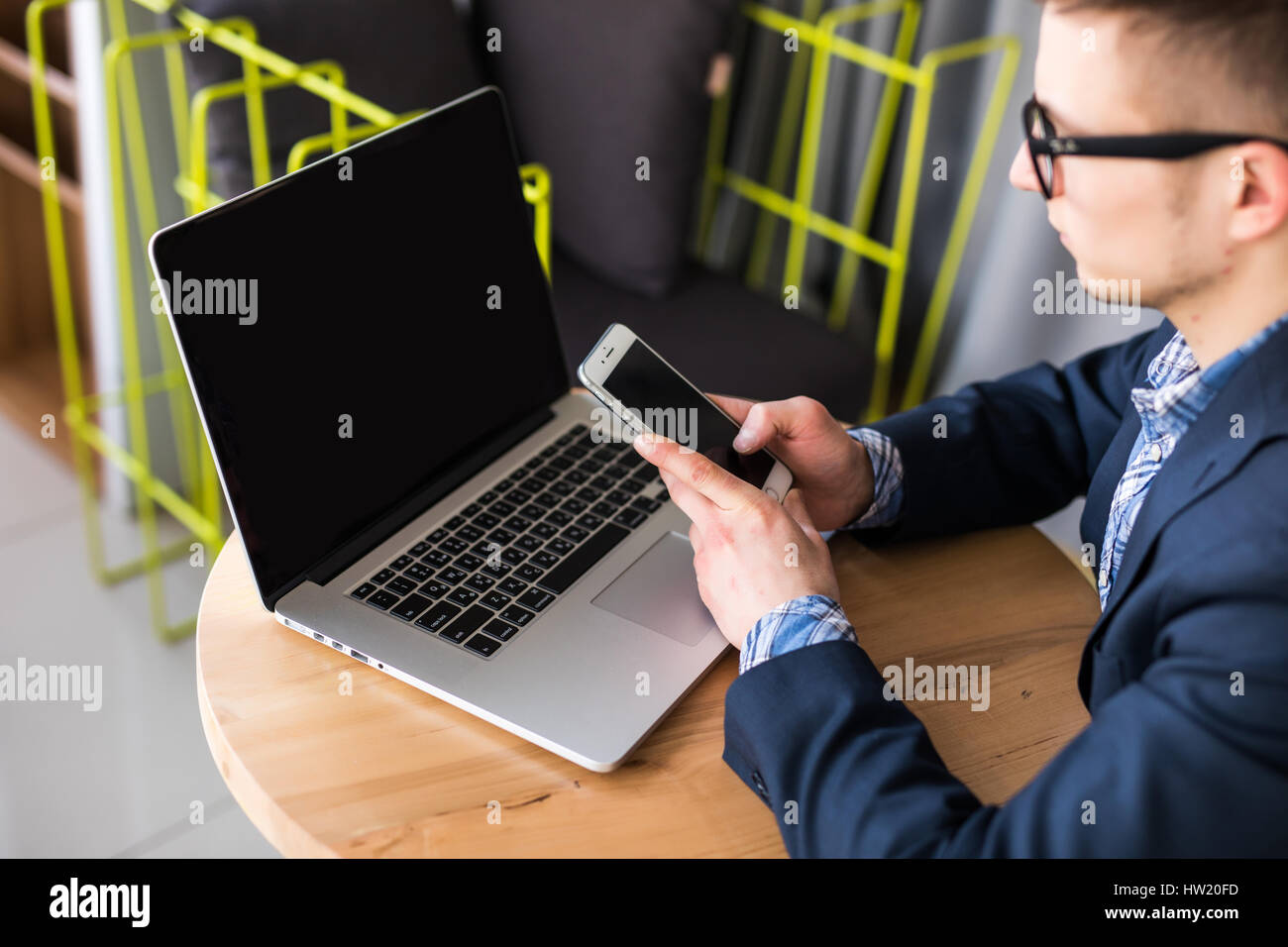 man typing on phone over laptop at wooden desk in cafe or office Stock ...