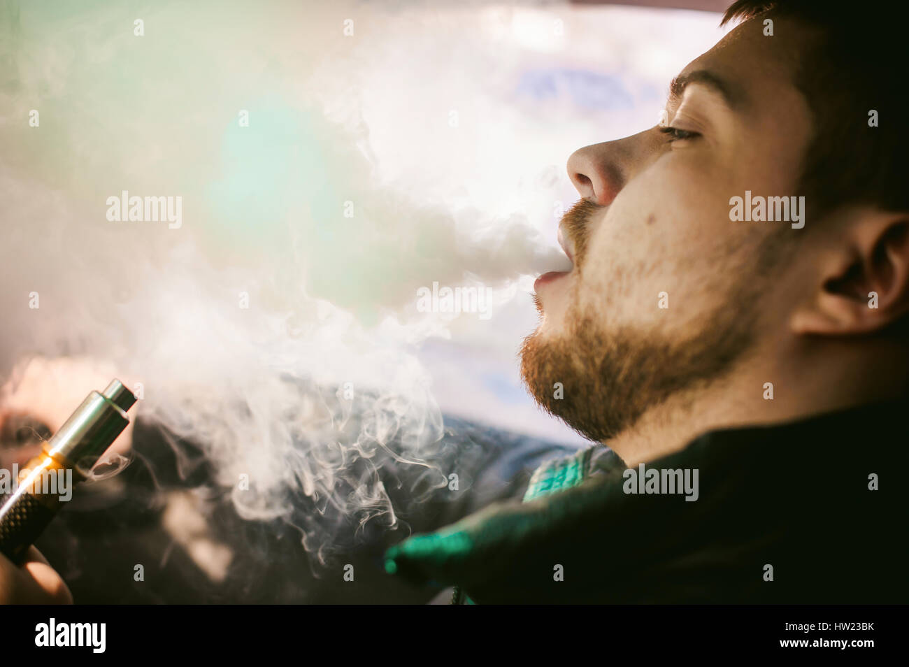 young vaper man with beard vaping mechanical mod. Guy smokes an ...