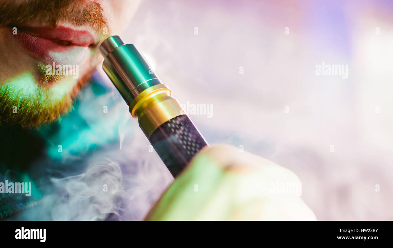 young vaper man with beard vaping mechanical mod. Guy smokes an ...