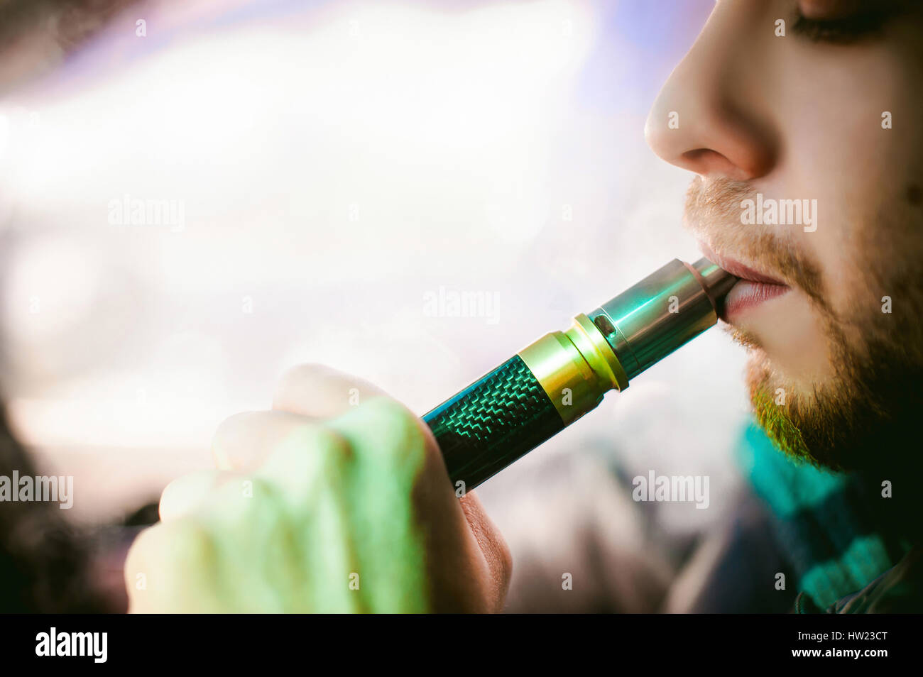 young vaper man with beard vaping mechanical mod. Guy smokes an ...
