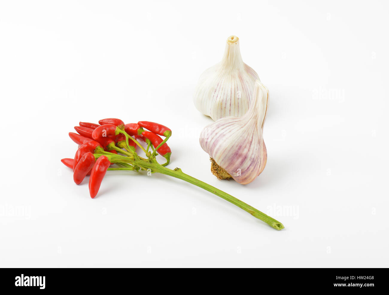 Bunch of small red chili peppers and garlic bulbs on white background ...