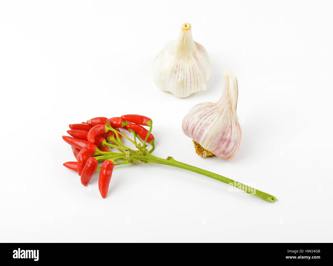 Bunch of small red chili peppers and garlic bulbs on white background ...