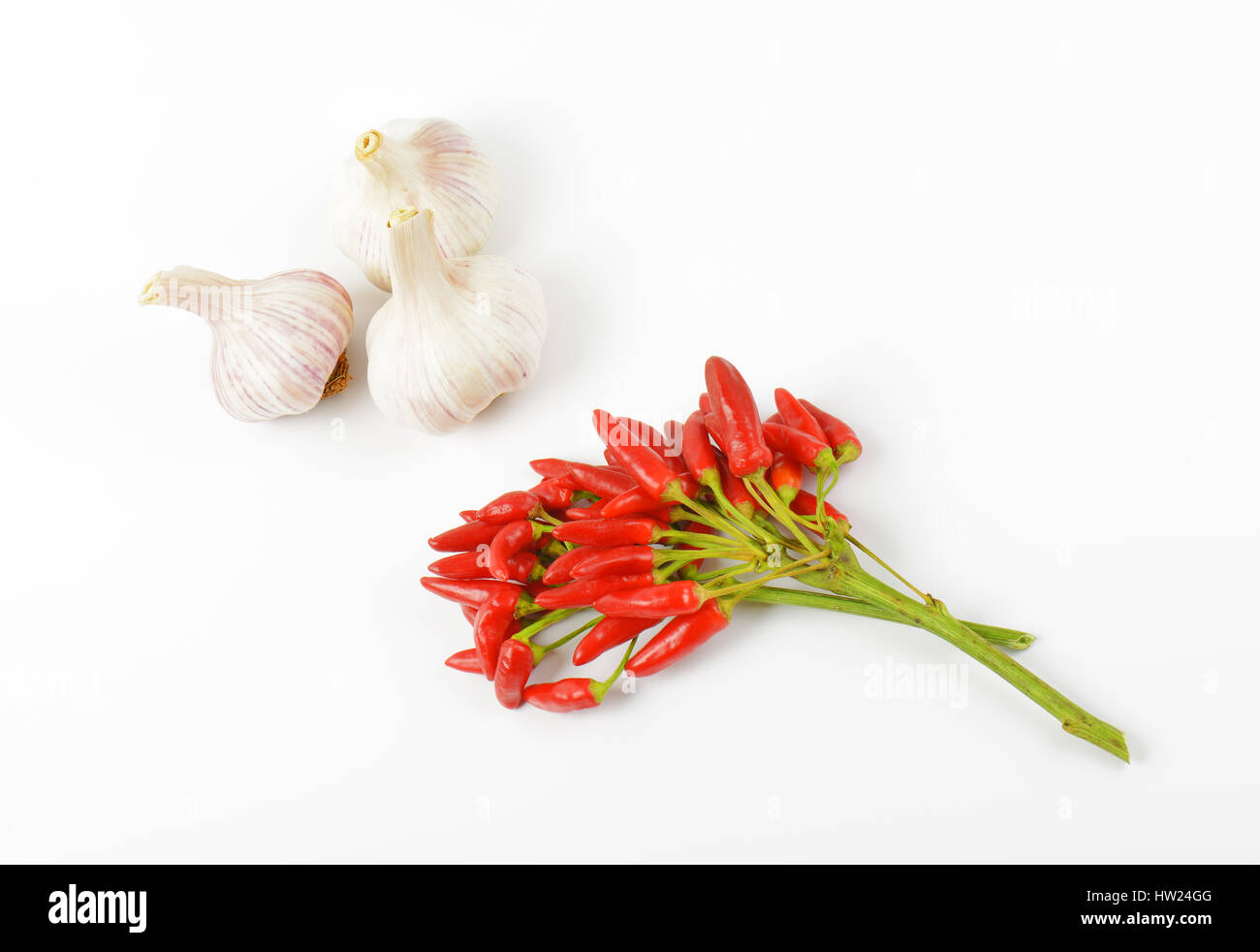 Bunch of small red chili peppers and garlic bulbs on white background ...