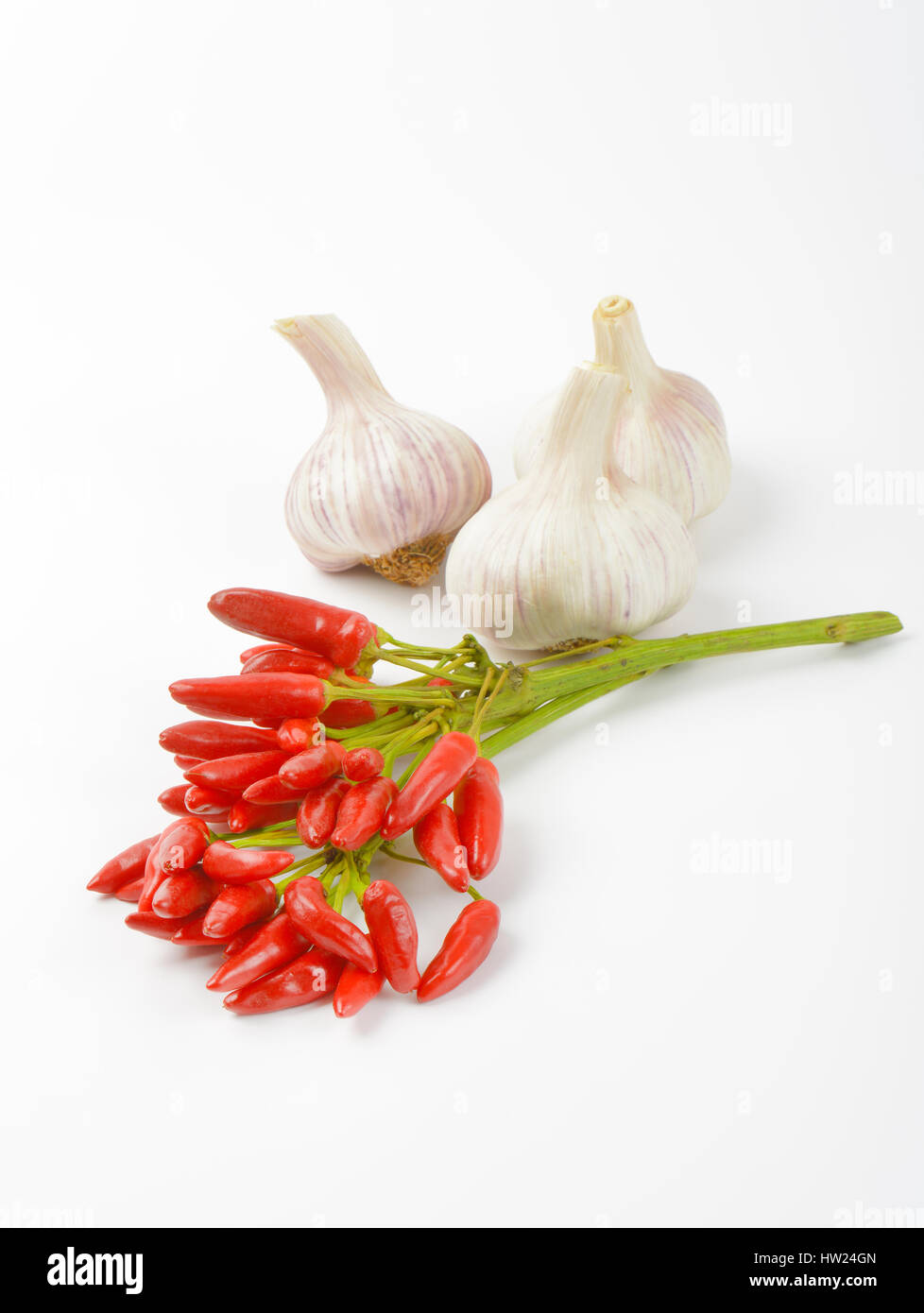 Bunch of small red chili peppers and garlic bulbs on white background ...
